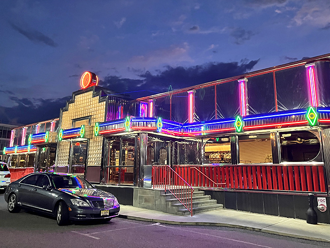 The neon-lit exterior of Tick Tock Diner transforms into a beacon of hope for hungry night owls, promising salvation in the form of comfort food at any hour.