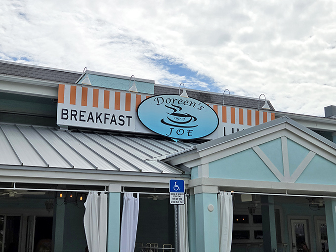 The cheerful blue exterior of Doreen's Cup of Joe beckons like a breakfast lighthouse on Marco Island, promising morning salvation under that iconic striped awning.