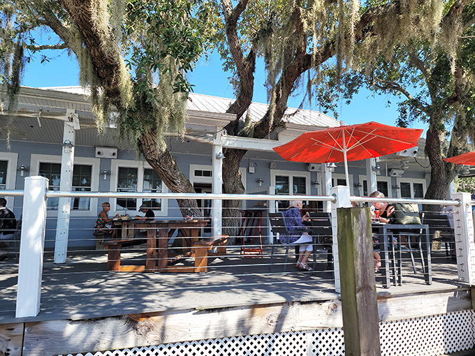 Diners enjoy waterfront meals under vibrant orange umbrellas on Aunt Kate's deck, where Florida's natural beauty enhances every bite.