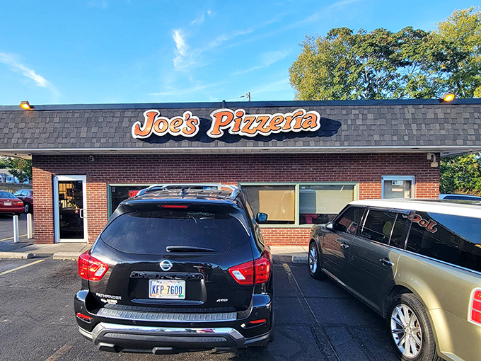 That iconic red sign beckons pizza pilgrims like a neon North Star. No fancy facade needed when what's inside has kept locals coming back for decades.