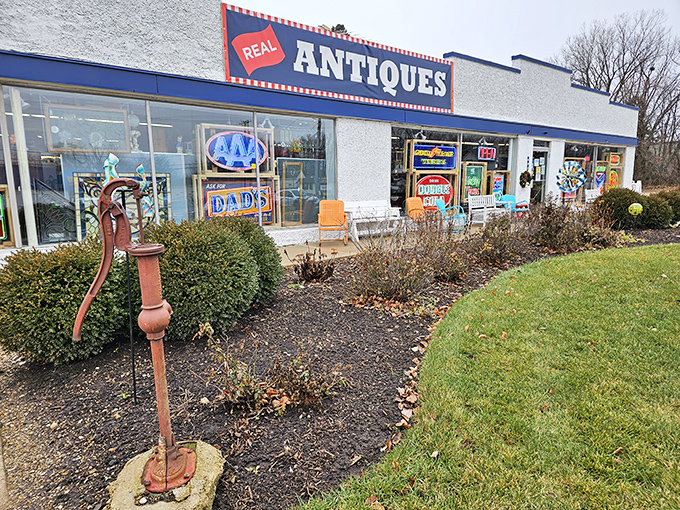 The blue-and-white facade of Roscoe Woodstock Antique Mall promises treasures within, while that vintage water pump stands guard like a rusty time sentinel.