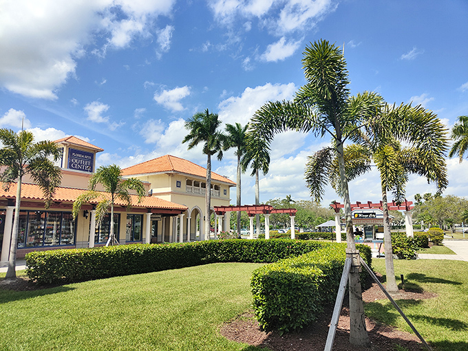 The Mediterranean-inspired architecture welcomes shoppers like a tropical mirage, promising retail therapy under swaying palm trees and blue Florida skies.