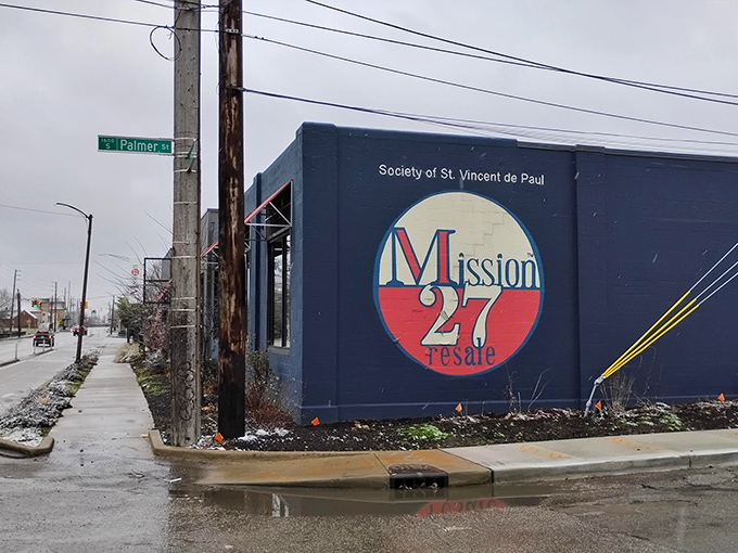 The navy-blue exterior with striking red awnings of Mission 27 Resale stands like a fashionable beacon on Shelby Street, promising treasure hunts without the sunburn.