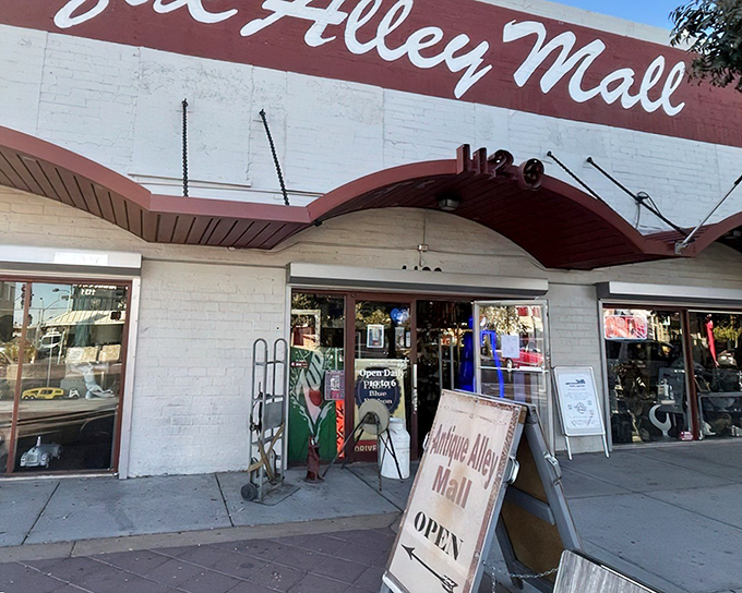 The unassuming exterior of Antique Alley Mall beckons with its vintage red awning, promising treasures within that the glitzy Strip could never imagine.