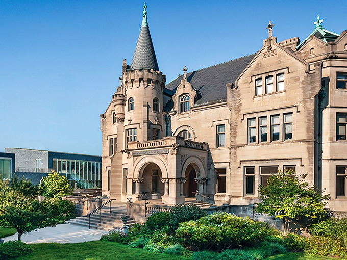 The Turnblad Mansion stands proudly against a blue Minnesota sky, its limestone turrets and arches whispering tales of old-world craftsmanship and new-world dreams.
