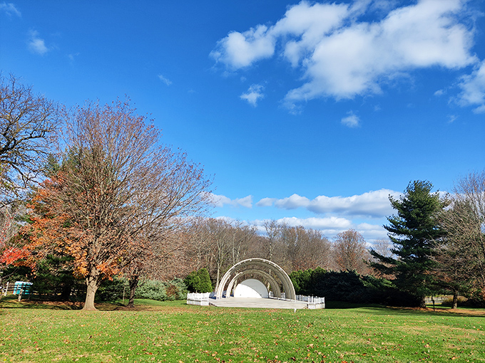 The historic bandshell at Bellevue State Park stands ready for summer concerts beneath autumn-tinged trees and a brilliant blue sky.