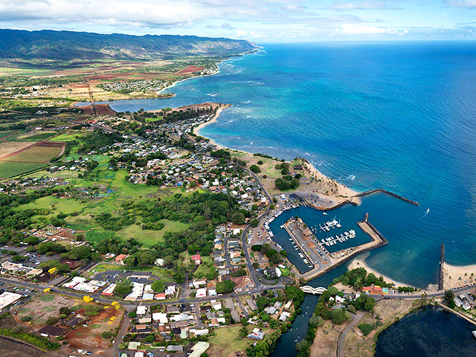 Aerial paradise: where turquoise waters meet lush landscapes. Haleiwa's harbor nestles perfectly between mountain and sea, like nature's own perfect composition.