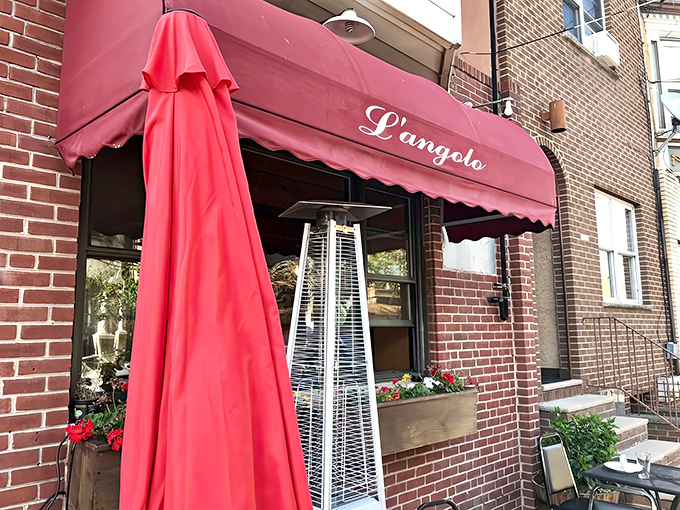 L'Angolo's entrance with its signature red awning and outdoor heater hints at the warm welcome waiting inside. Even the plants look happy to be here.