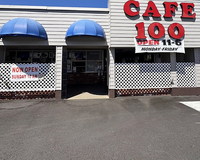The unassuming exterior of Cafe 100 with its bright red signage and blue awnings&mdash;proof that culinary treasures often hide in plain sight.