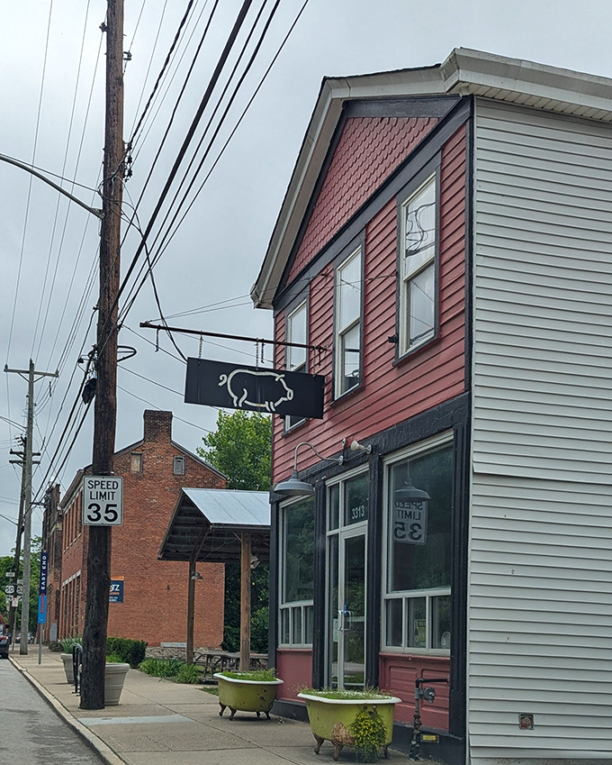 The unassuming red exterior of Eli's BBQ stands like a beacon of hope for hungry souls – that pig sign isn't just decoration, it's a promise of smoky delights within.