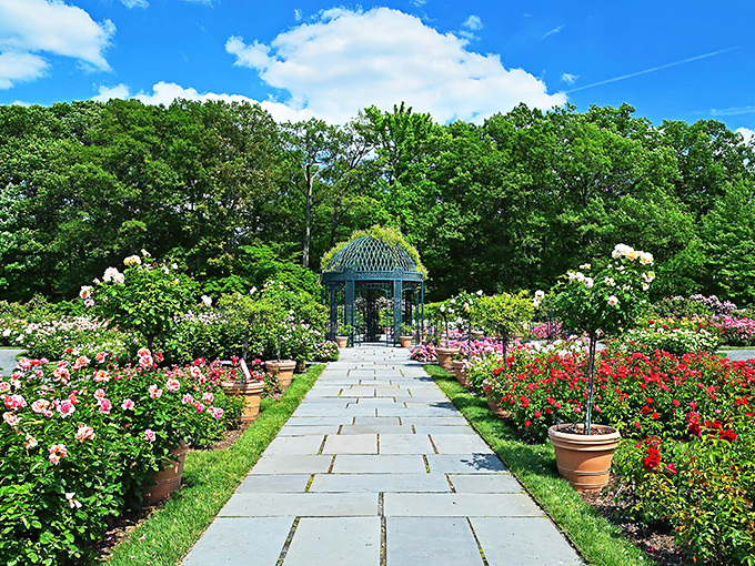 A stone pathway flanked by roses leads to a gazebo that looks like it was designed by someone who read too many Jane Austen novels&mdash;in the best possible way.