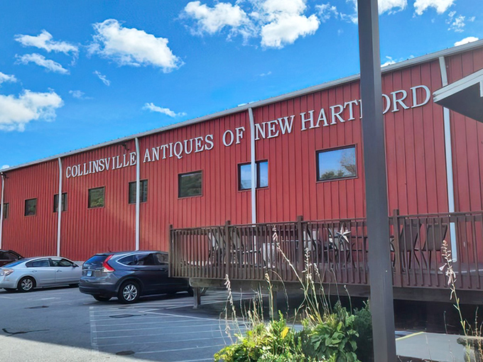 The iconic red barn exterior of Collinsville Antiques stands like a beacon for treasure hunters against the Connecticut sky, promising adventures in every aisle.