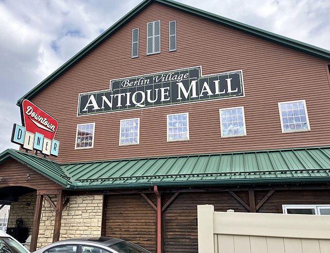 The rustic barn-like exterior of Berlin Village Antique Mall stands as a beacon to treasure hunters, promising adventures in nostalgia beneath that distinctive green roof.