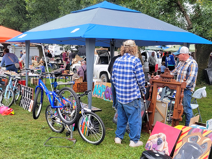 Treasure hunters browse under blue canopies while vintage bicycles wait for their next adventure. Every aisle promises unexpected discoveries.