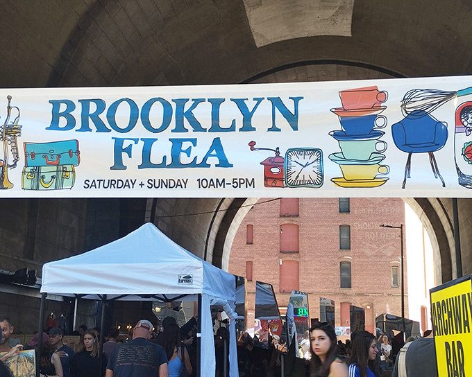 The iconic Brooklyn Flea banner welcomes treasure hunters under DUMBO's majestic archway. Weekend plans just got exponentially more interesting!