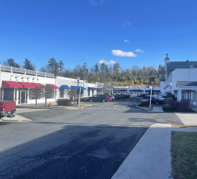 The classic New England architecture of Lee Premium Outlets stands against a brilliant blue Berkshire sky, proving shopping paradise can be scenic too.