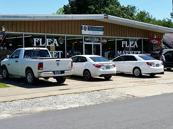 The unassuming exterior of The Junk House Flea Market beckons treasure hunters with its straightforward promise &ndash; adventures await behind those glass doors, no fancy marketing required.