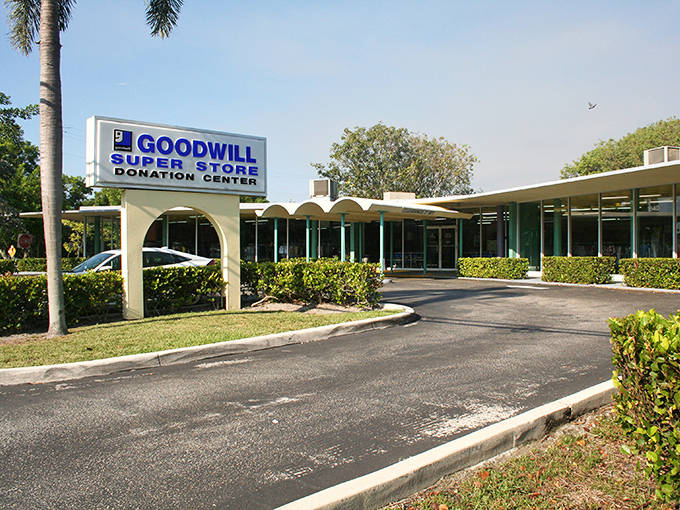 The iconic blue Goodwill sign stands like a beacon of bargain possibilities, palm trees swaying as if applauding your smart shopping decision.