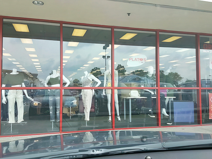 Mannequins modeling current trends behind Plato's Closet's signature red-framed windows &ndash; fashion's silent salespeople making you rethink your wardrobe choices.