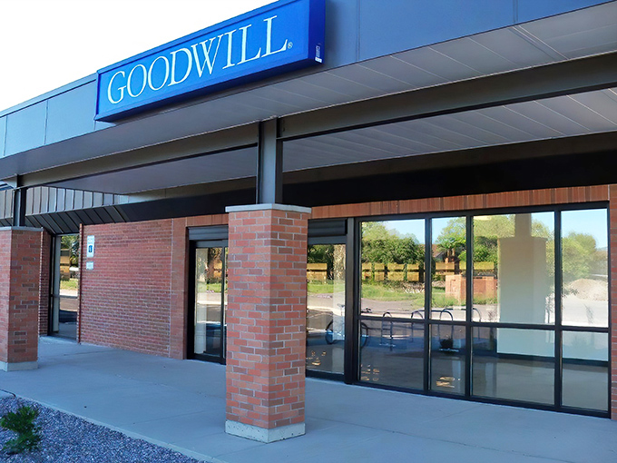 The iconic blue Goodwill sign beckons like a thrift siren, promising treasures within those brick walls that would make any bargain hunter's heart race.