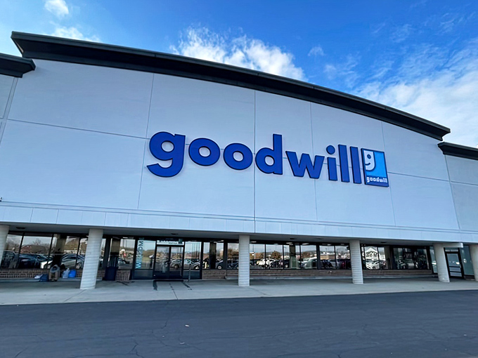The blue Goodwill sign beckons like a lighthouse for bargain hunters, promising treasures within this unassuming Columbus strip mall location.
