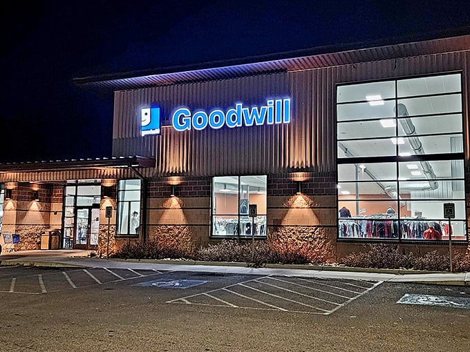 The blue Goodwill sign glows like a beacon of bargain hope against the night sky, promising treasures within those illuminated windows.