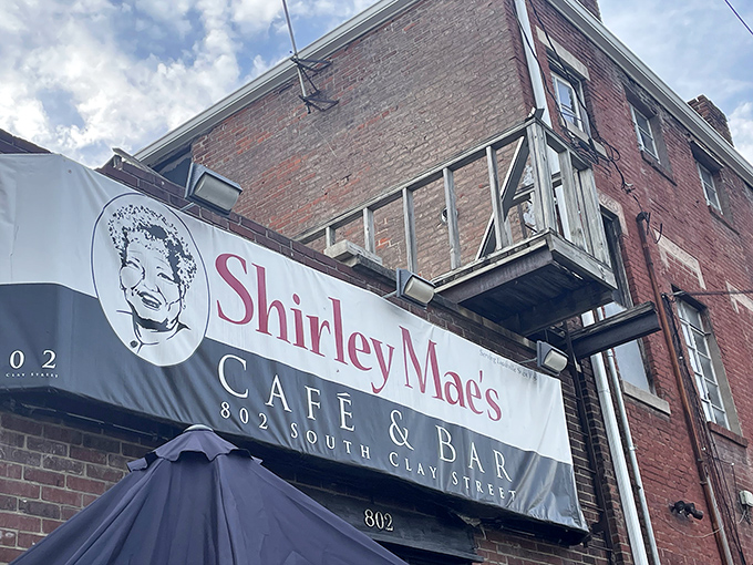 The unassuming brick facade of Shirley Mae's Caf&eacute; & Bar stands as Louisville's culinary time capsule, promising soul food treasures behind its modest exterior.