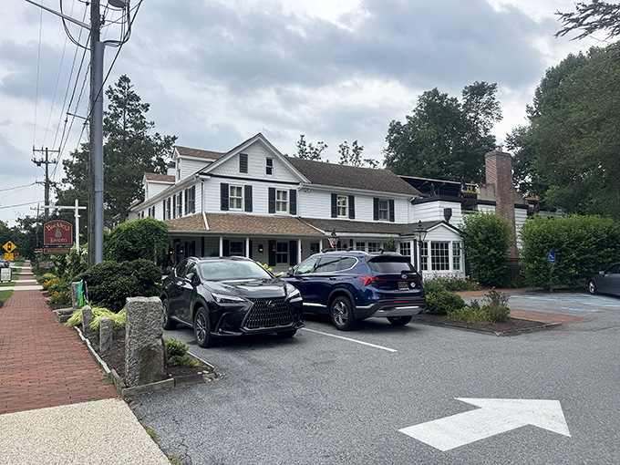 The classic white colonial exterior of Buckley's Tavern welcomes you like an old friend, complete with lush greenery and that iconic red sign promising good times ahead.
