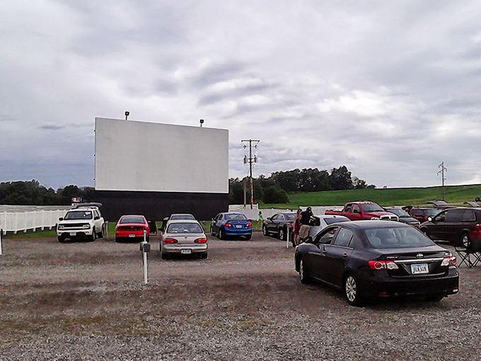 Cars lined up facing the massive white screen, each vehicle a private theater under Iowa's vast sky. Movie magic awaits as dusk approaches.