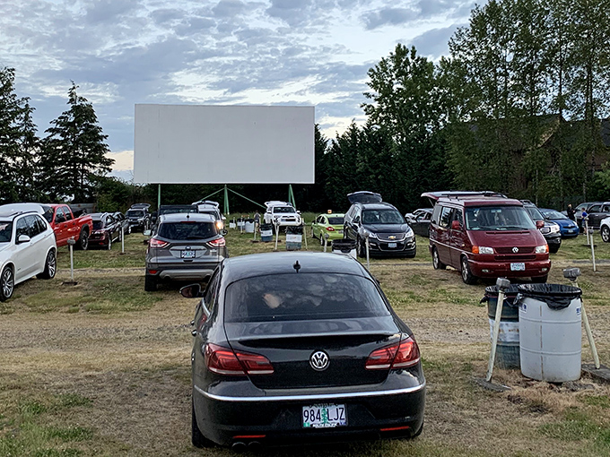 Cars lined up like eager moviegoers themselves, facing the blank canvas that will soon burst into cinematic life as twilight approaches.
