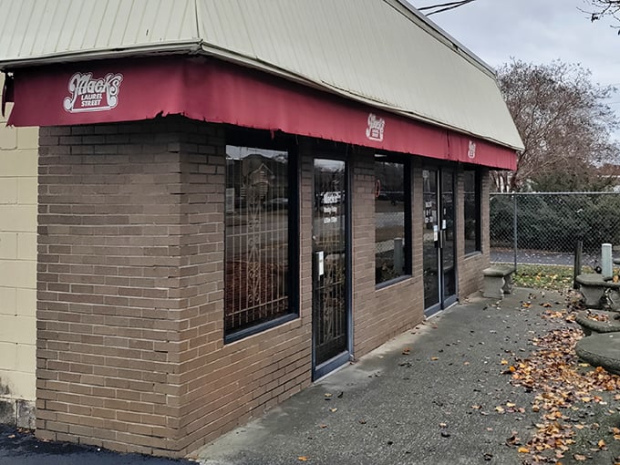 The unassuming exterior of Mack's Cash Grocery, where culinary treasures hide behind brick walls and a weathered red awning. Food paradise rarely announces itself with neon signs.