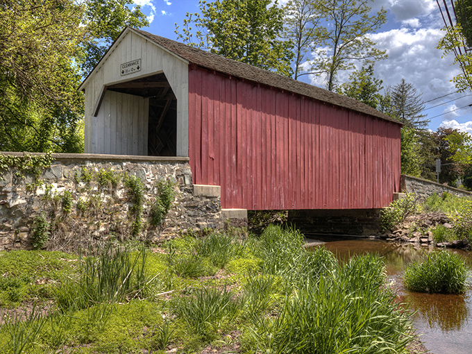 Sunlight plays across the weathered red siding, where Tohickon Creek flows beneath this architectural time capsule. Some things just get better with age&mdash;like this bridge and most cheeses.