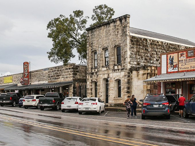 Historic limestone buildings line Bandera's Main Street, where modern vehicles park alongside structures that have witnessed a century of Texas tales.
