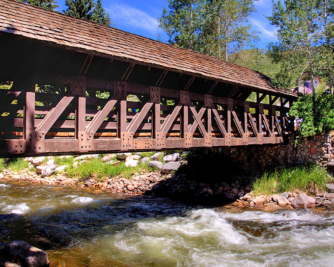 The classic wooden lattice design of Vail's covered bridge offers a perfect frame for your Colorado mountain memories, complete with charming red railings and stone foundations.