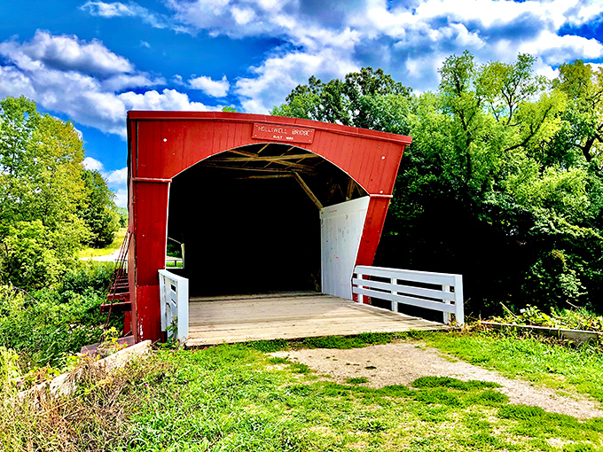 The crimson facade of Holliwell Bridge welcomes visitors like an old friend, standing proudly against Iowa's impossibly blue summer sky.