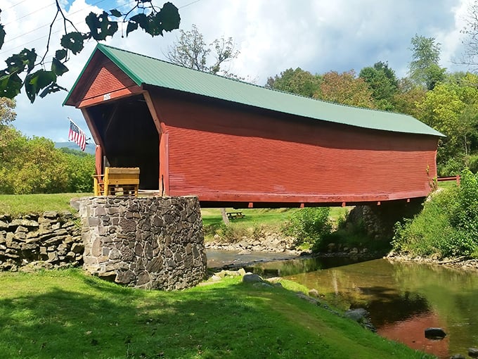 The Clover Hollow Covered Bridge stands like a crimson sentinel against Virginia's rolling hills, its reflection dancing in the stream below.