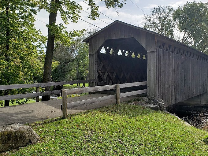 Wisconsin's last covered bridge stands proudly beside its historical marker, a wooden time capsule spanning Cedar Creek since 1876.