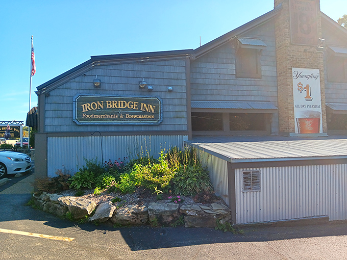 The Iron Bridge Inn stands proudly under Pennsylvania's blue skies, its distinctive black awnings and stone foundation promising culinary adventures within.