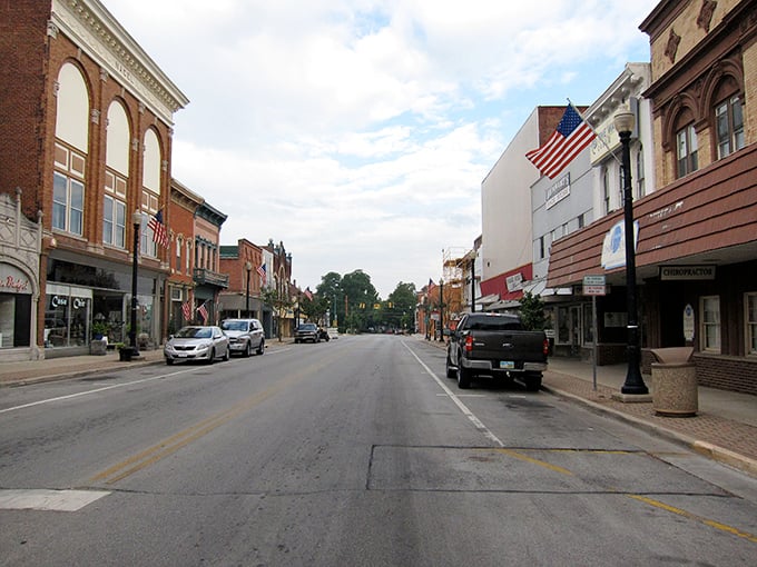 Auglaize Street stretches into the distance, American flags fluttering above storefronts that have witnessed decades of small-town life.