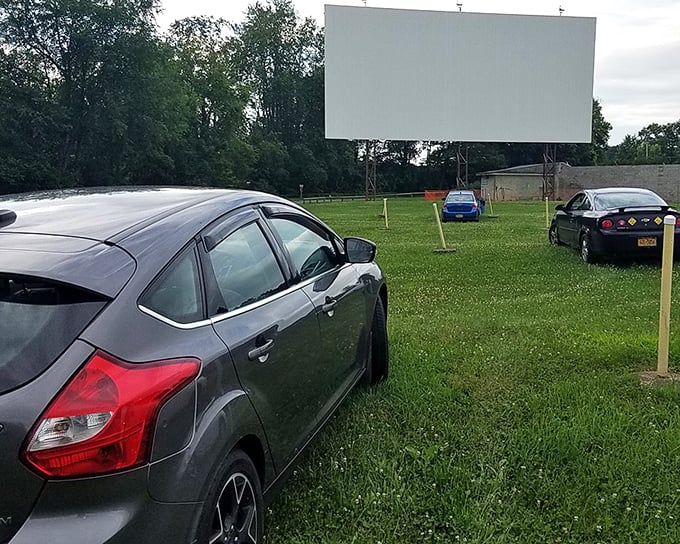 Cars lined up facing cinema's holy grail&mdash;a massive white screen awaiting dusk's transformation into movie magic. The perfect marriage of automotive comfort and cinematic wonder.