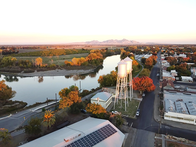 Sunset paints Colusa in golden hues as the Sacramento River curves gracefully around this hidden gem. The iconic water tower stands sentinel over tree-lined streets.
