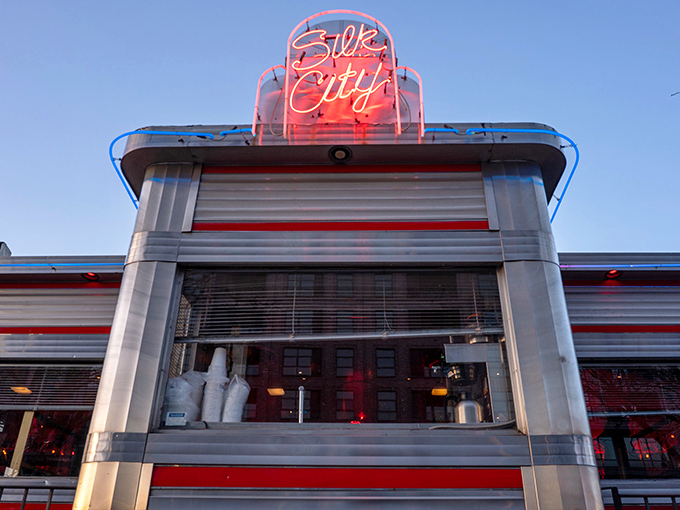 That iconic neon sign beckons like a lighthouse for the hungry, promising retro charm and modern flavors beneath its rosy glow.