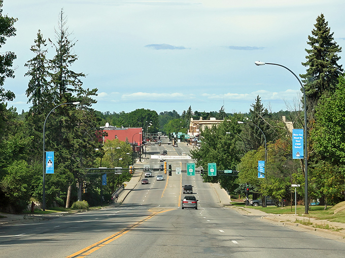 Main Street stretches toward the horizon like a welcome mat, flanked by towering pines that have witnessed generations of Grand Rapids life unfold.