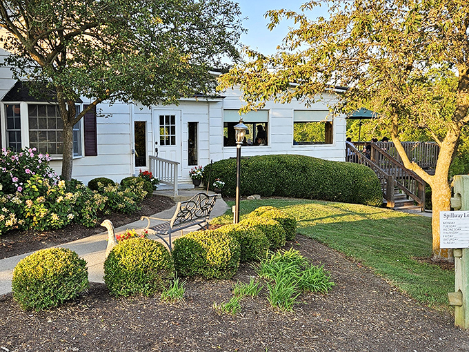 The charming white exterior of Spillway Lodge welcomes you like an old friend, complete with manicured landscaping and a bench perfect for savoring the anticipation.