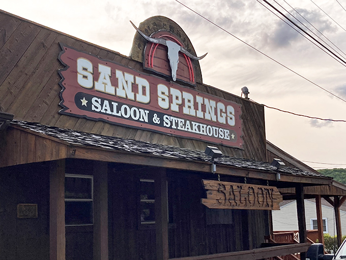 The iconic wooden facade and cattle skull sign of Sand Springs Saloon & Steakhouse welcomes hungry travelers like a frontier outpost for modern appetites.