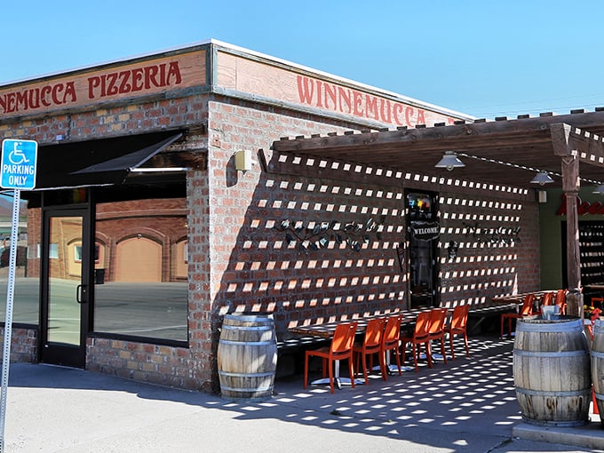 The classic brick exterior of Winnemucca Pizzeria, where wooden lattice creates a mesmerizing shadow play on the outdoor patio.