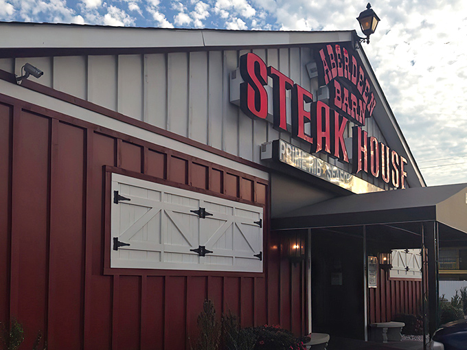 The classic red barn facade glows like a beacon for hungry souls seeking steak salvation after dark.