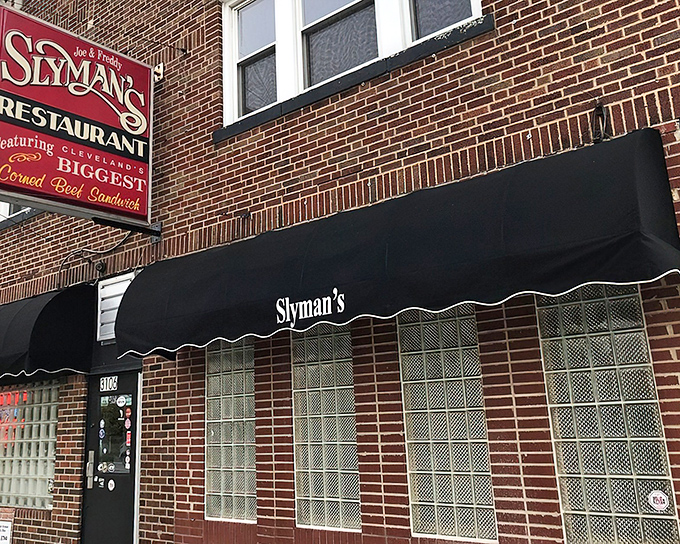 Slyman's unassuming brick exterior with its classic black awning&mdash;proof that the most extraordinary culinary treasures often hide in plain sight.