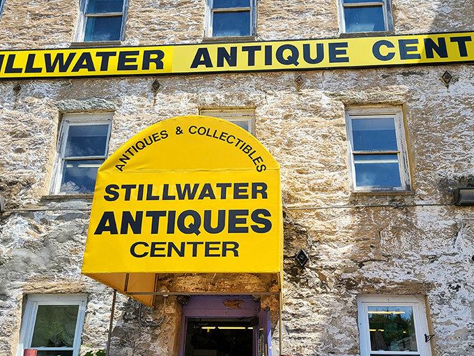 The iconic yellow awning of Stillwater Antique Center stands out against the historic stone building like a beacon for treasure hunters.