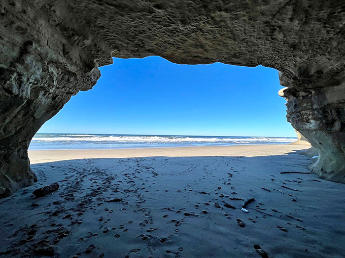 Looking out from the cave, the beach feels quiet, with waves tracing gentle patterns along the shoreline.